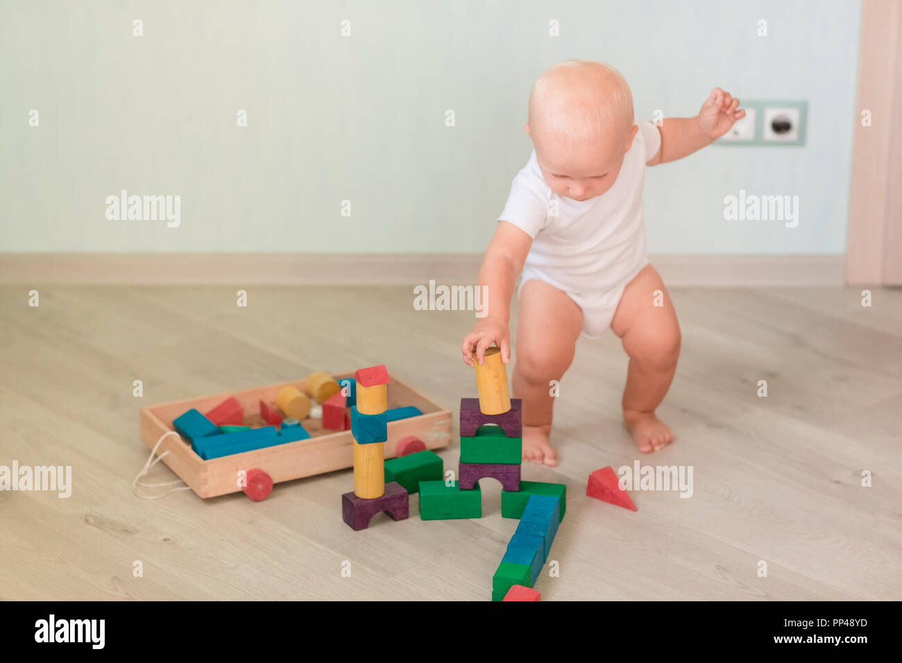 Cute little baby playing with colored wooden blocks in the room. Early ...