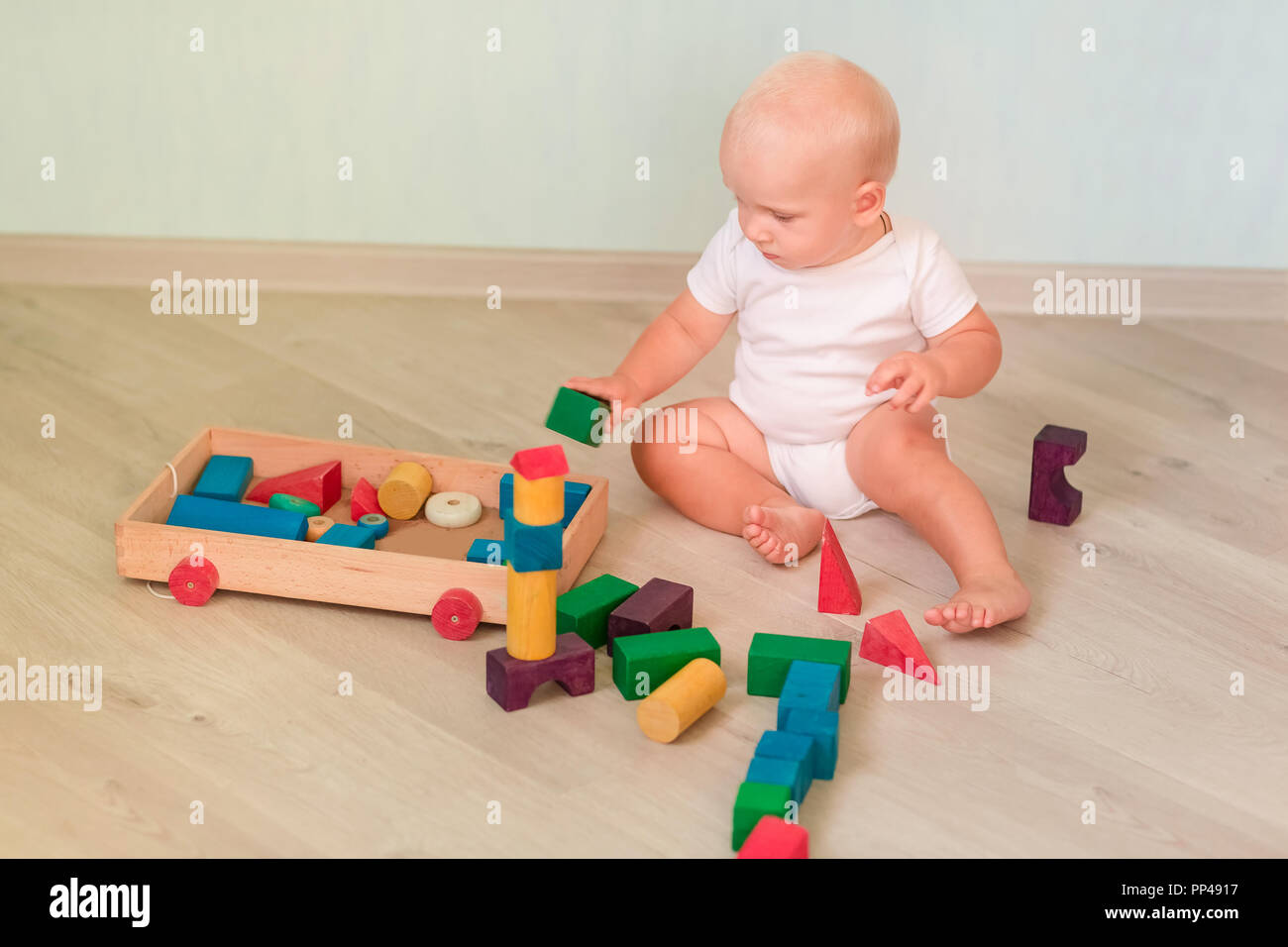 Cute little baby playing with colored wooden blocks in the room. Early ...