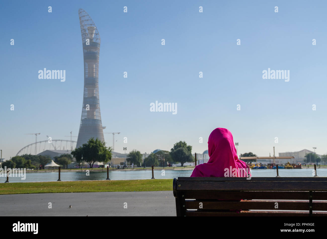 Muslim woman sitting on the bench in Aspire Park Doha, Qatar Stock ...