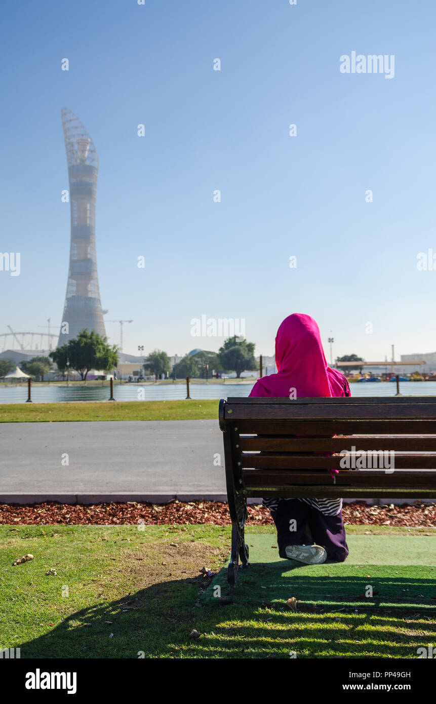 Muslim woman sitting on the bench in Aspire Park Doha, Qatar Stock ...