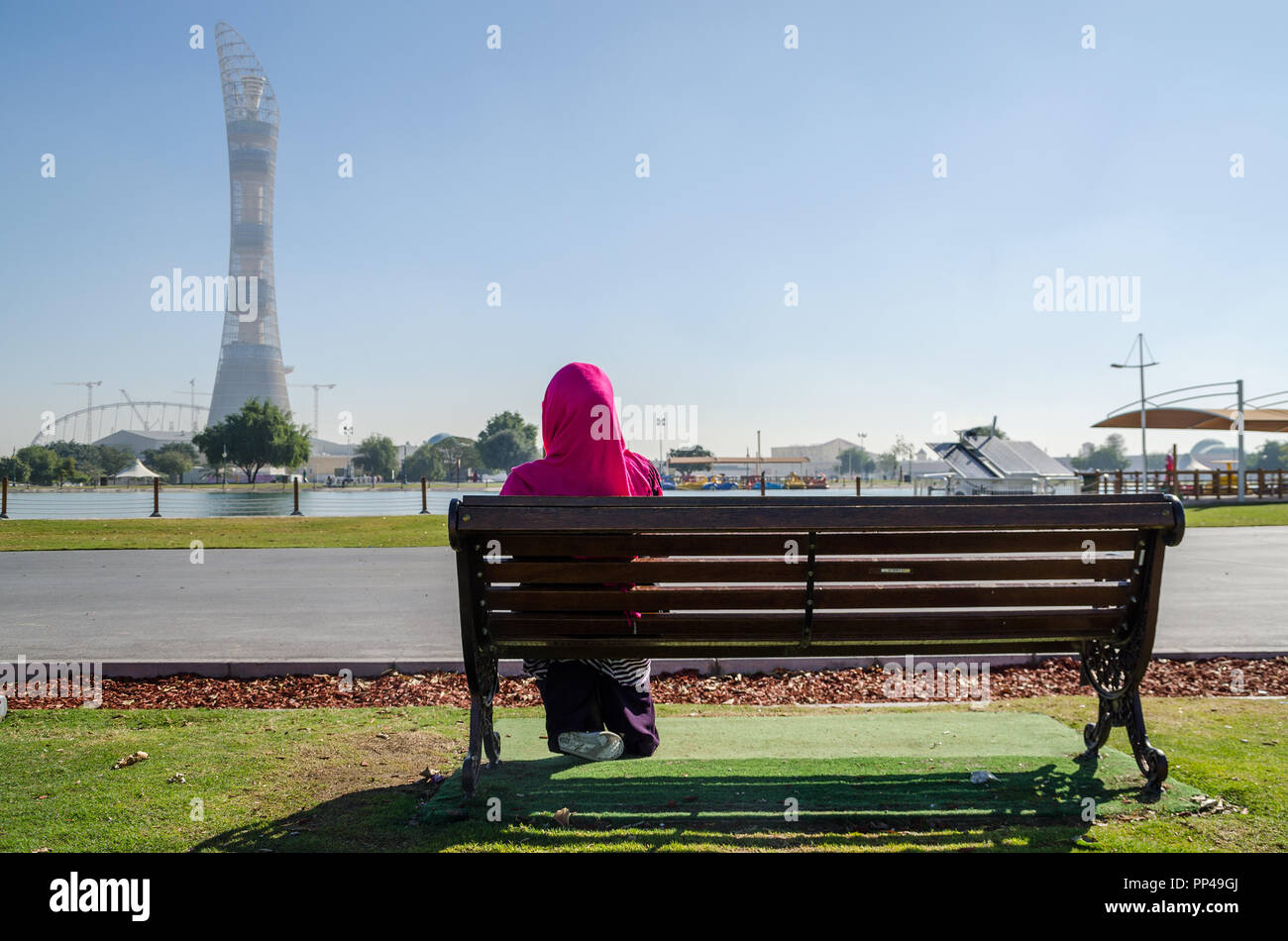 Muslim woman sitting on the bench in Aspire Park Doha, Qatar Stock ...