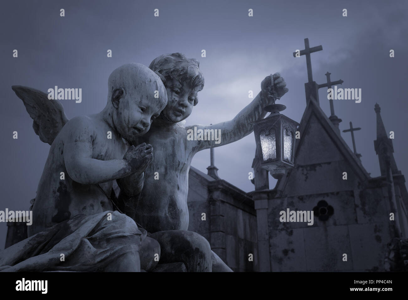 Child angels statue with a lamp in the hand of an old european cemetery ...