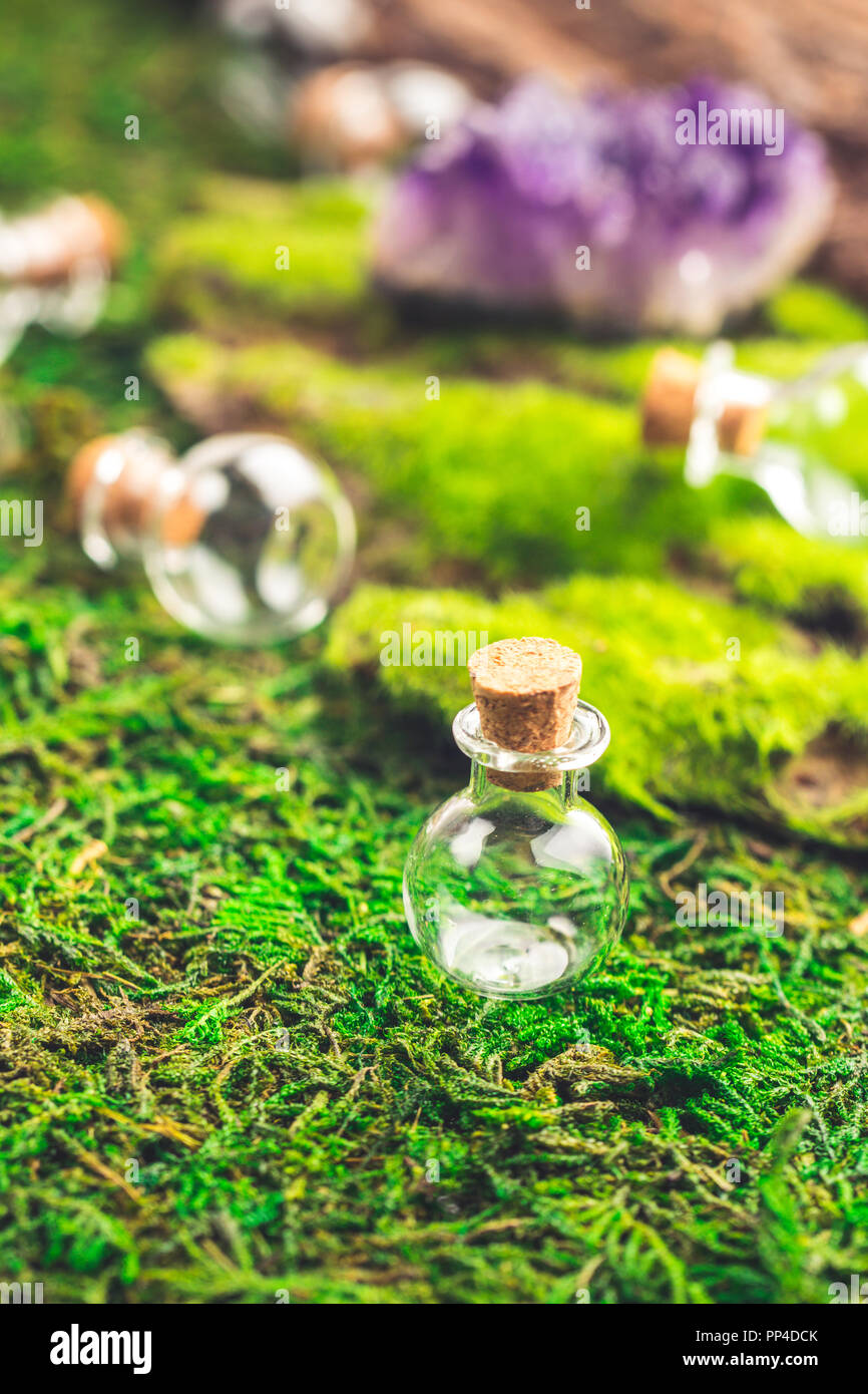 Magic flask and amethyst stone on emerald moss in the forest. Halloween ...