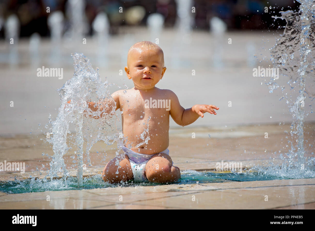 Children, refreshing on a very hot summer day, walking in fountain ...