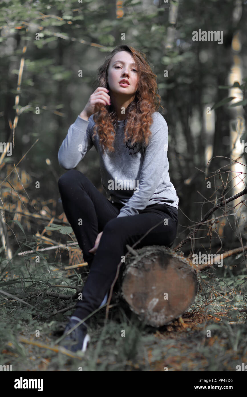beautiful young woman sitting on a log Stock Photo - Alamy