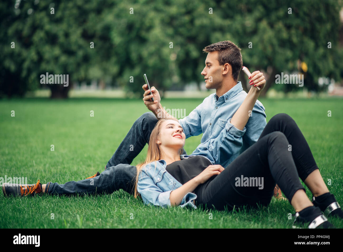 Phone addicted people, couple lies on the grass and using their ...