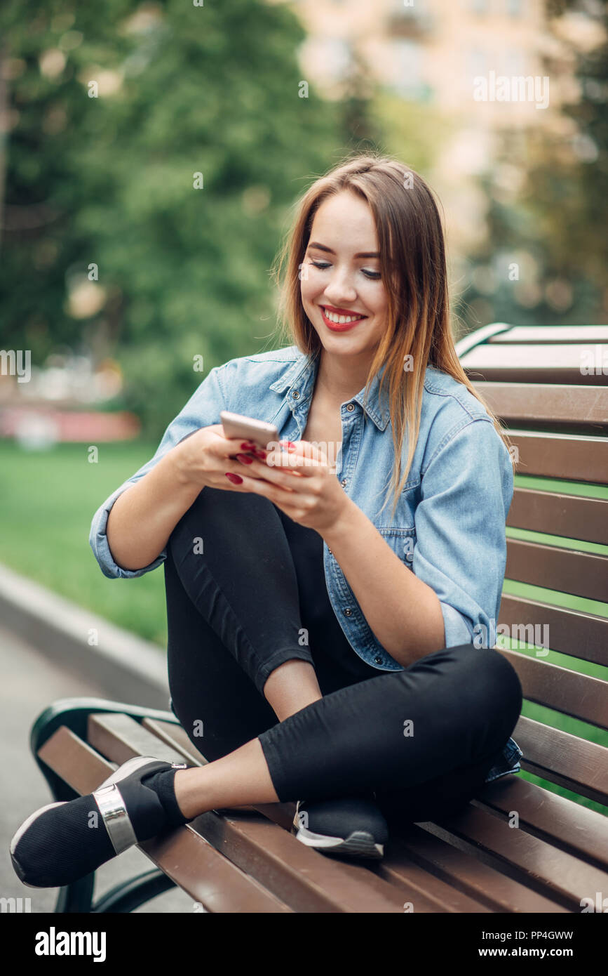 Phone addiction, addict woman using smartphone on the bench in park ...