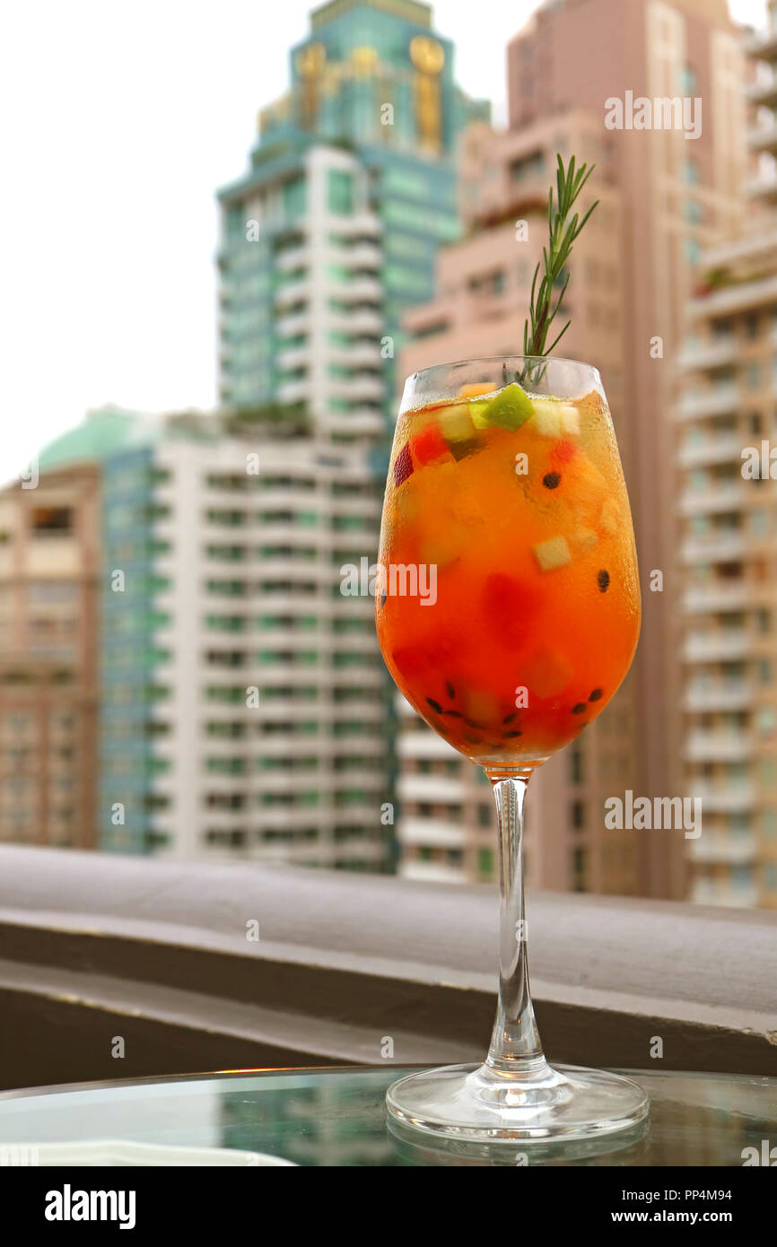 Glass of vibrant orange color fresh fruit cocktail at the roof top bar ...
