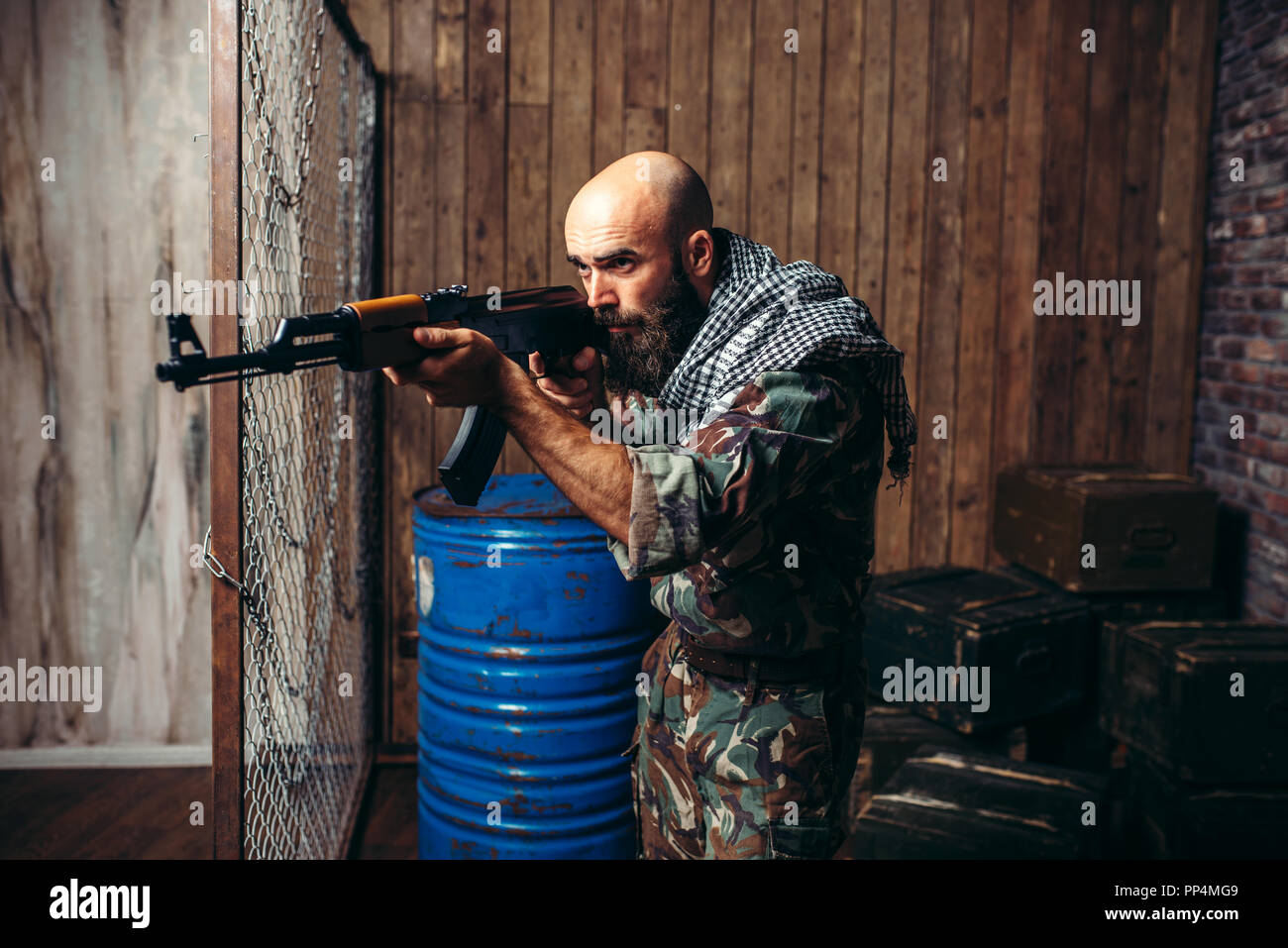 Terrorist in uniform aiming from a kalashnikov rifle, male mojahed with ...