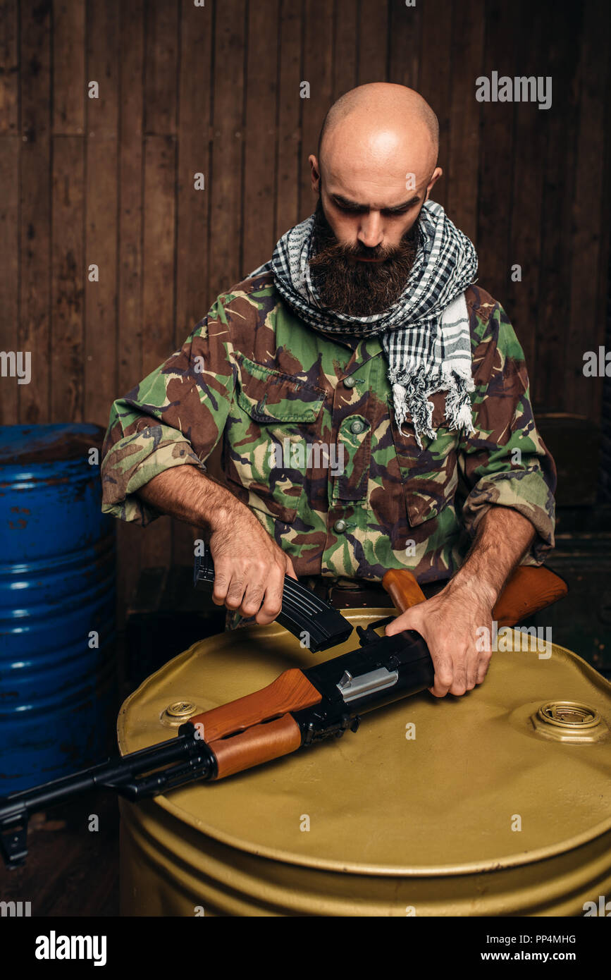 Terrorist in uniform inserts the magazine into the kalashnikov rifle ...