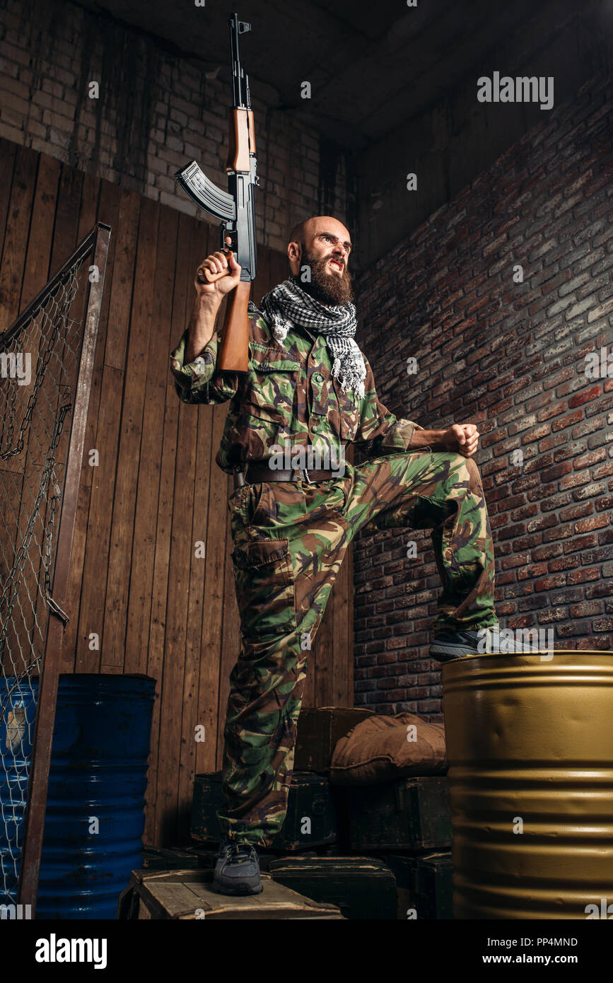 Terrorist in uniform with kalashnikov rifle raised his hands up, male ...