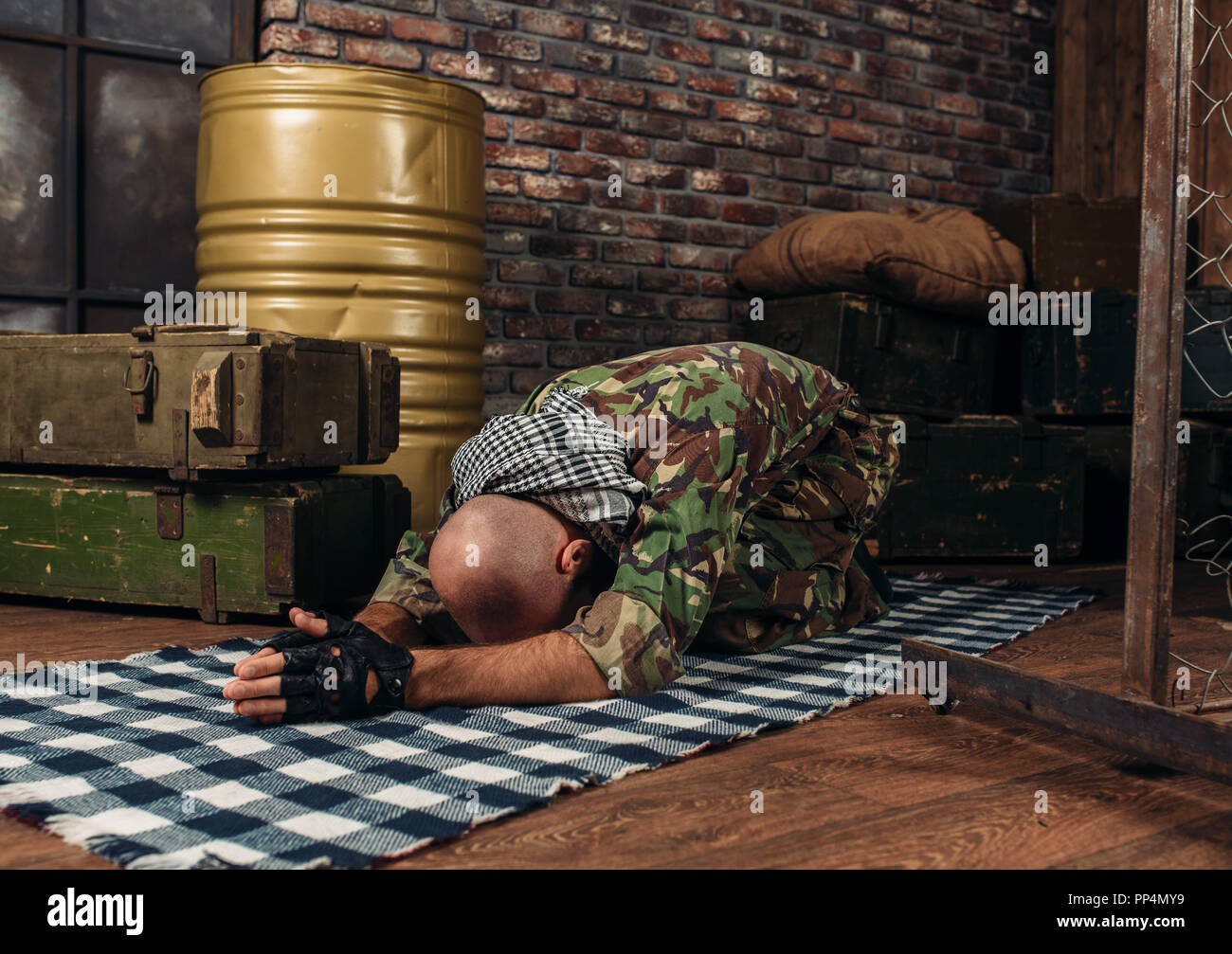 Islam soldier in uniform praying before a terrorist attack, barrels of ...