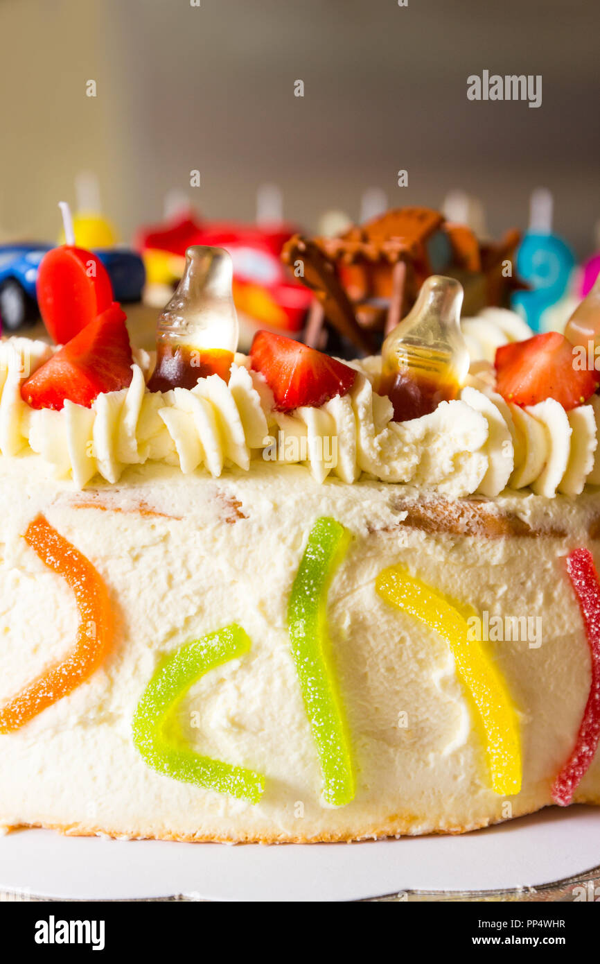 Birthday cake with fruit, candy and whipped cream - side view shallow ...