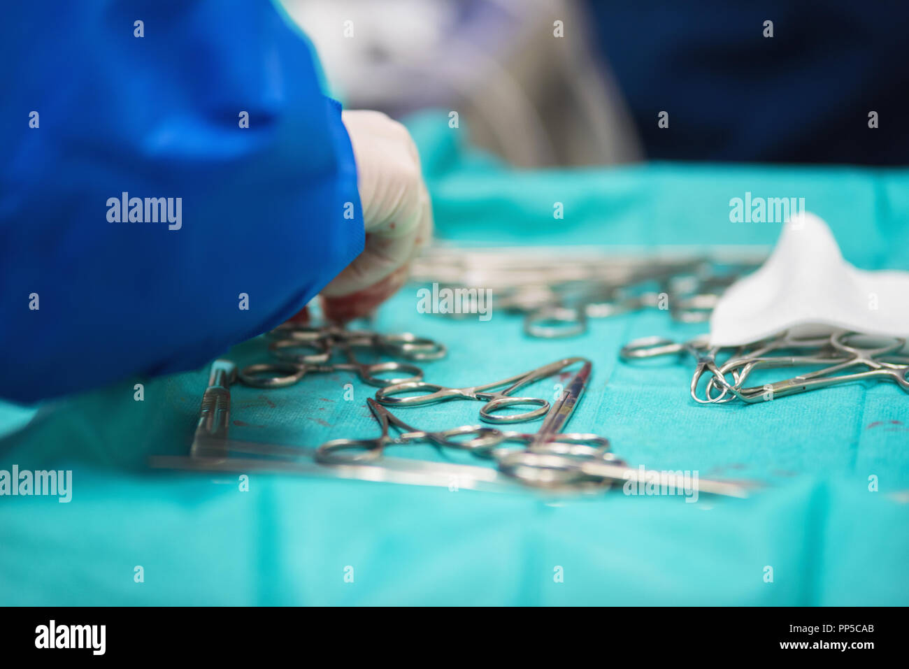 Surgeon hand picking up an instrument from tray of surgical instruments ...