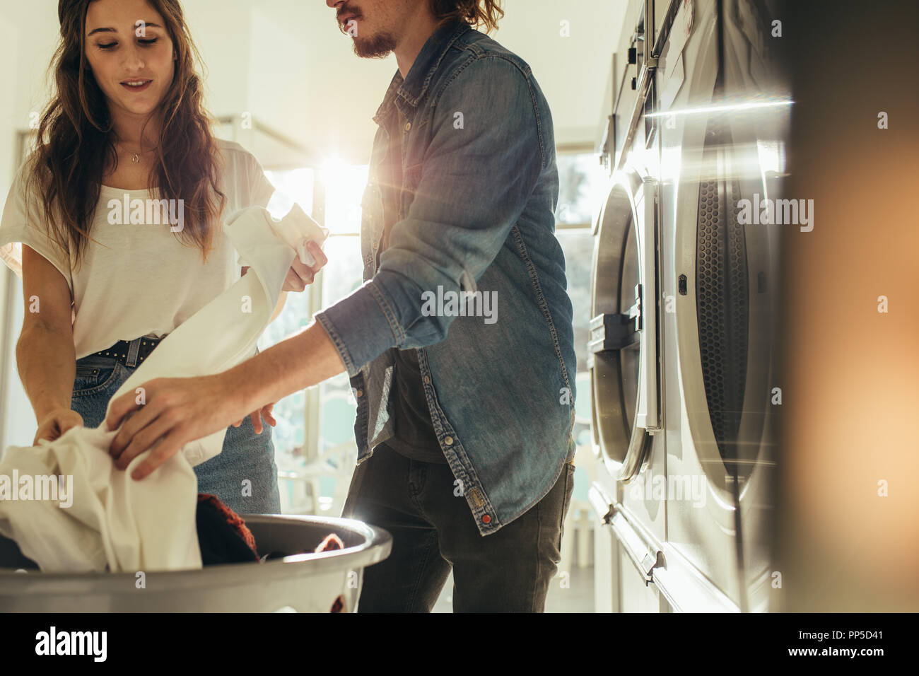 Couple doing laundry together picking clothes from a basket. Couple in ...