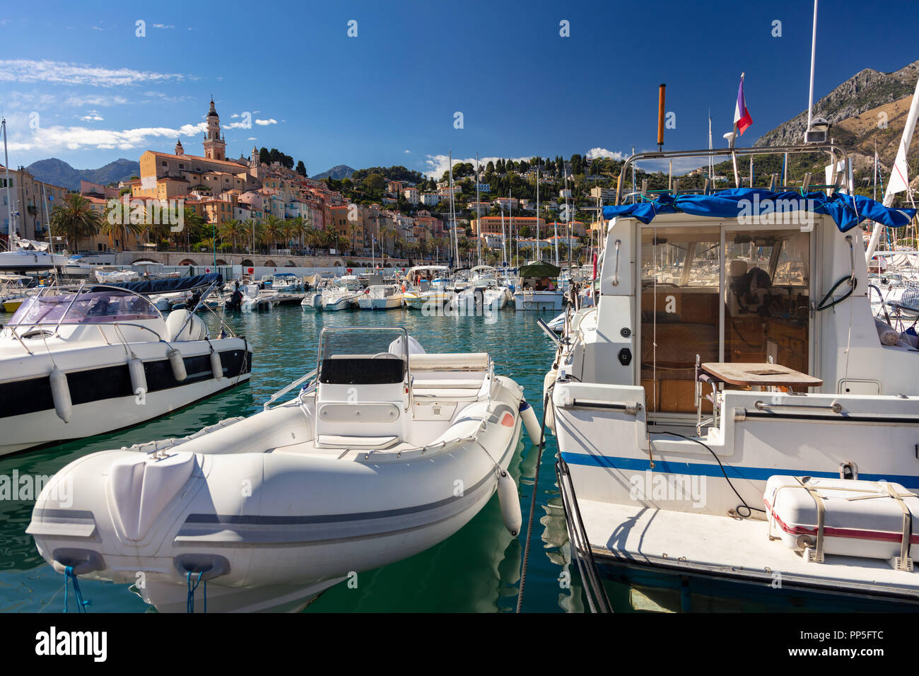 Boats in Menton harbor on the French Riviera and the Basilique Saint ...