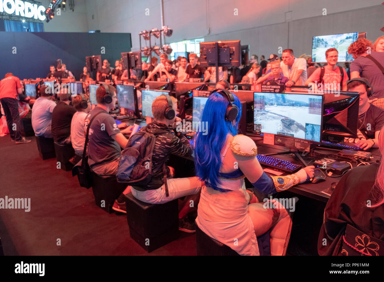 Visitor in cosplay costume sitting in front of a military computer game ...