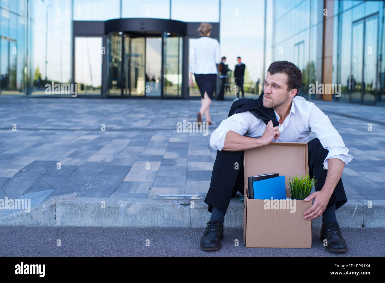 Fired business man sitting frustrated and upset on the street near ...