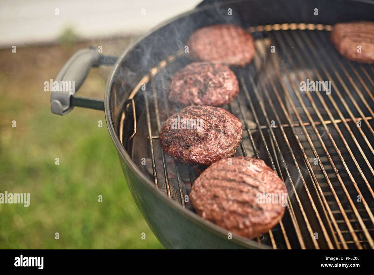 Burgers cooking on a grill Stock Photo - Alamy