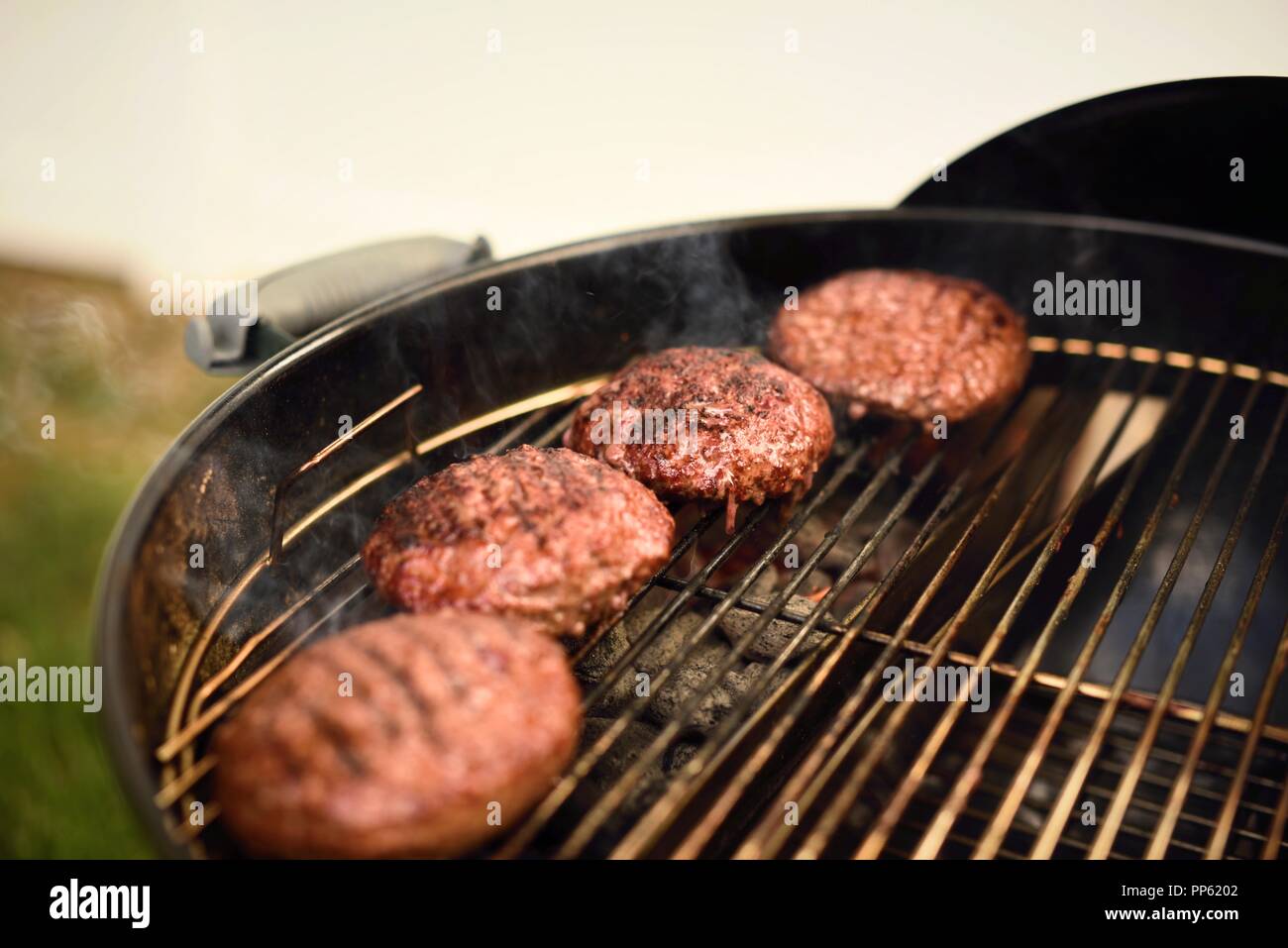 Burgers cooking on a grill Stock Photo - Alamy