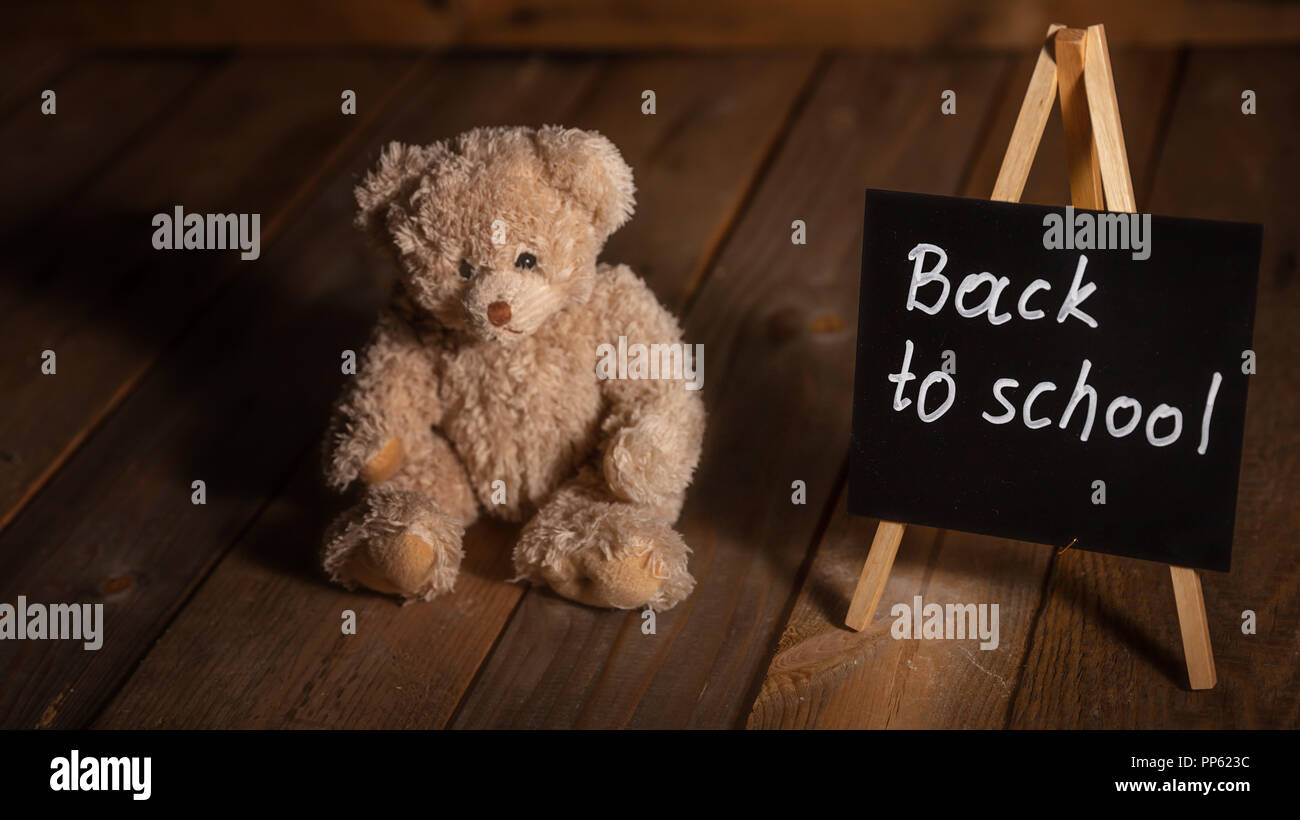 Back to school. Teddy bear sitting on floor, blackboard with back to ...
