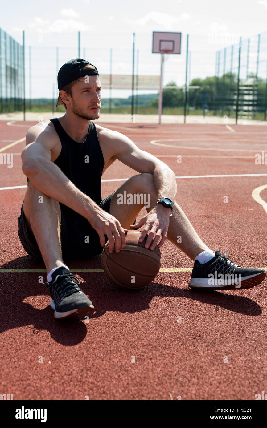 Young Man Resting in Basketball Court Stock Photo - Alamy