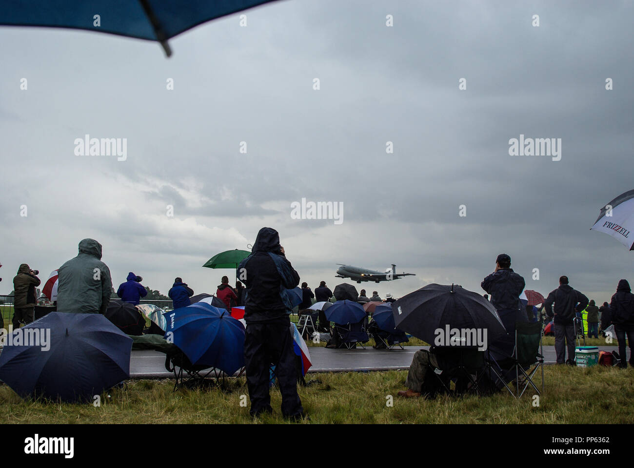 Wet aviation enthusiasts in the rain at an airshow as a RAF Nimrod jet ...