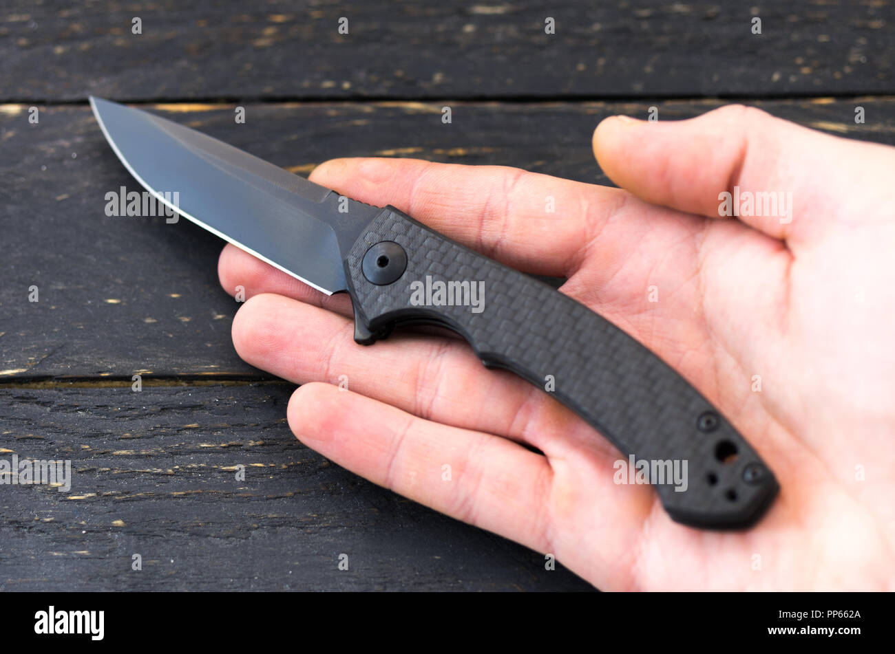 Black pocket knife in hand. Knife in the right hand. Compact pocket ...