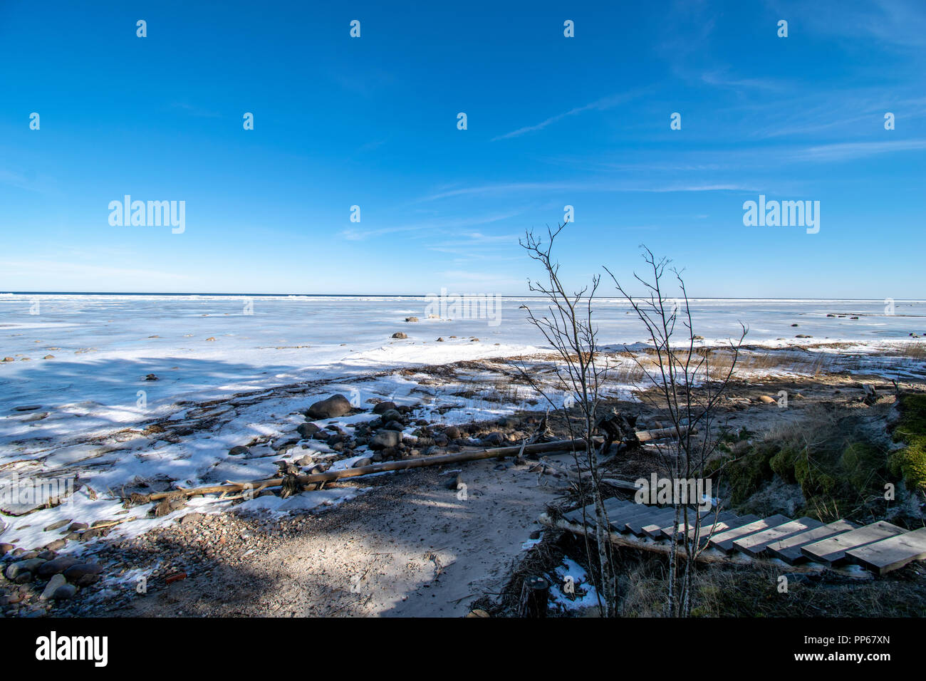 frozen lake shore in winter with footsteps in the snow and ice blocks ...