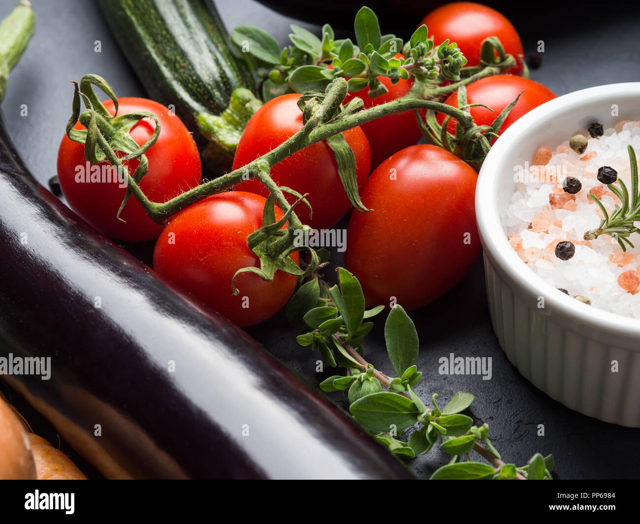 Mix of raw vegetables with salt, spices on dark background. Clean ...