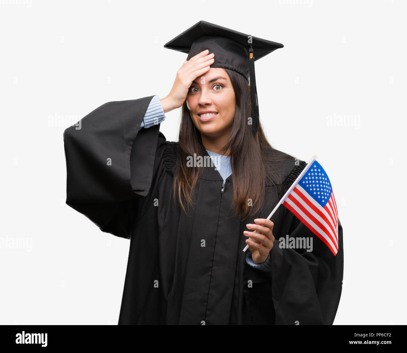 Young hispanic woman wearing graduated uniform holding flag of america ...