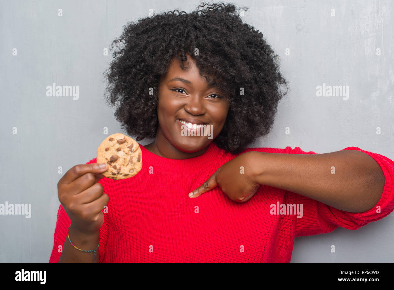 Young african american woman over grey grunge wall eating chocolate ...