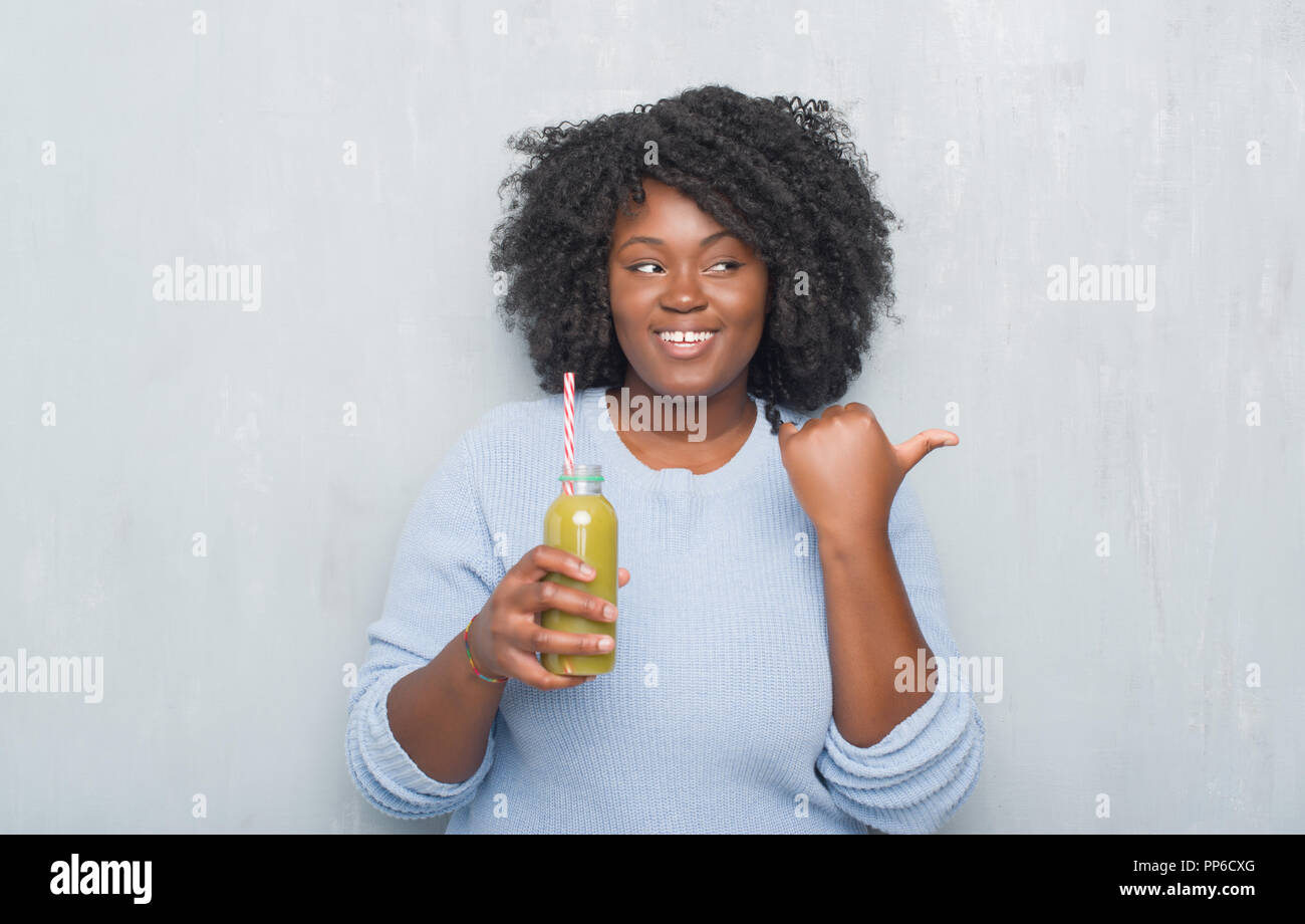 Young african american woman over grey grunge wall drinking detox green ...