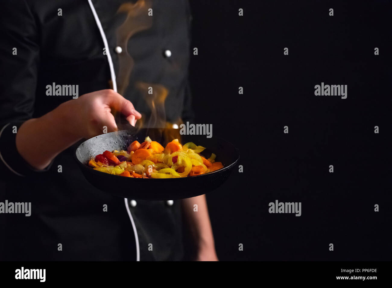 Professional chef and fire. Cooking vegetables and food over an open ...