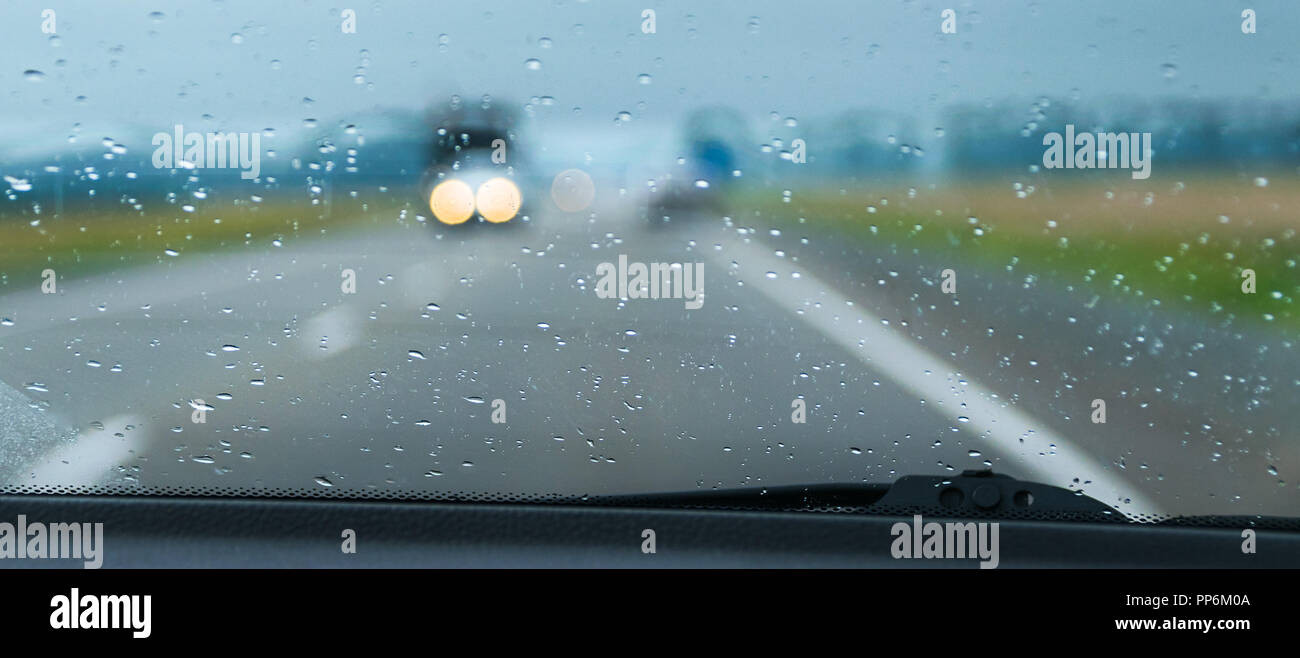 Blurred traffic lights seen through the rain drops on the windscreen of ...