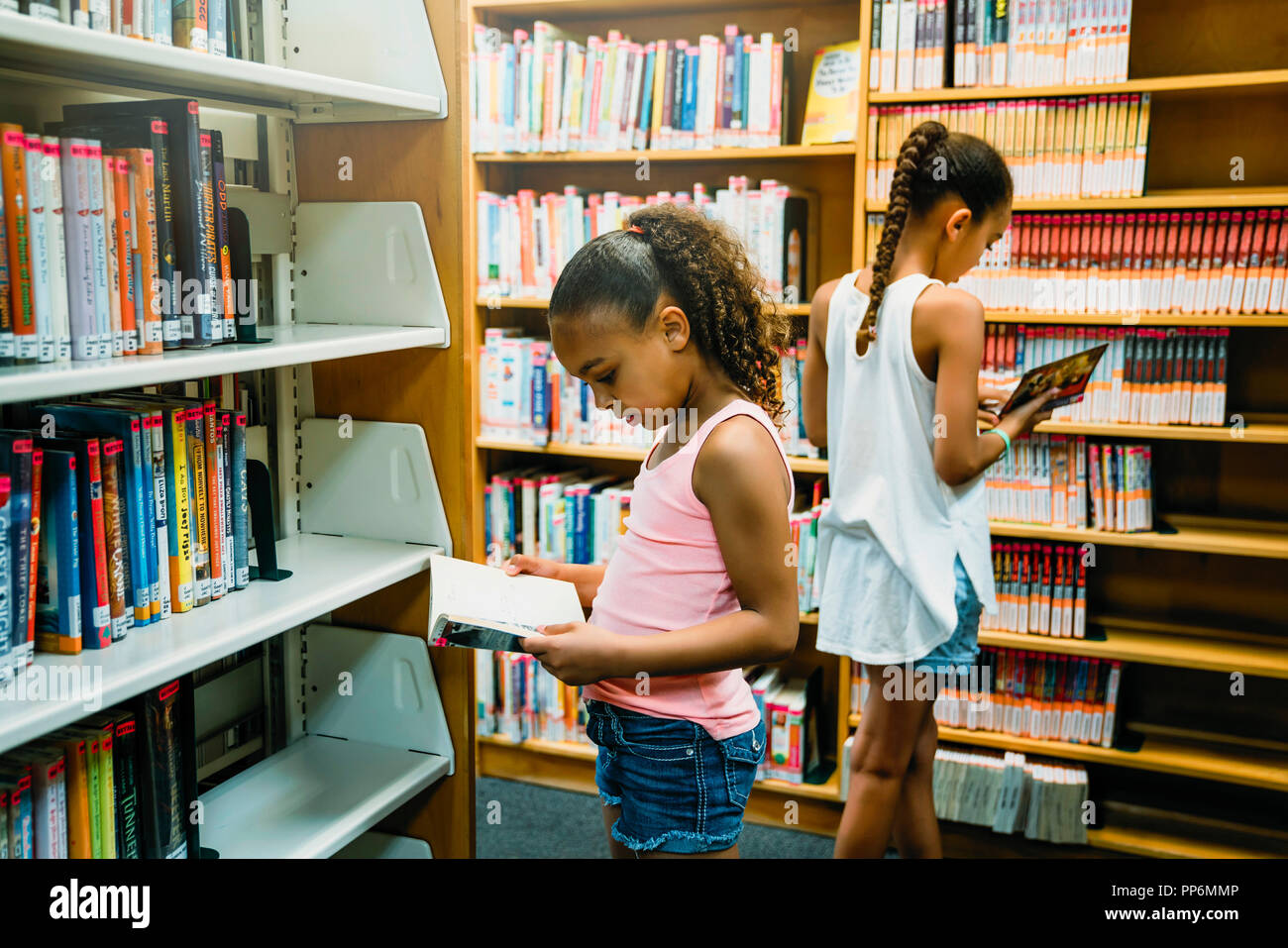 Girls looking at books in public library Stock Photo - Alamy