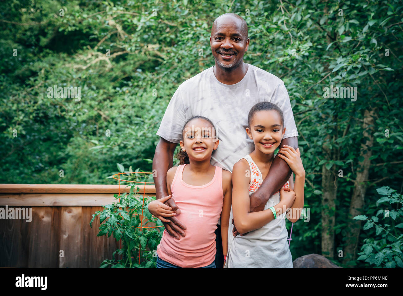 Portrait of happy dad hugging daughters in front of house Stock Photo ...