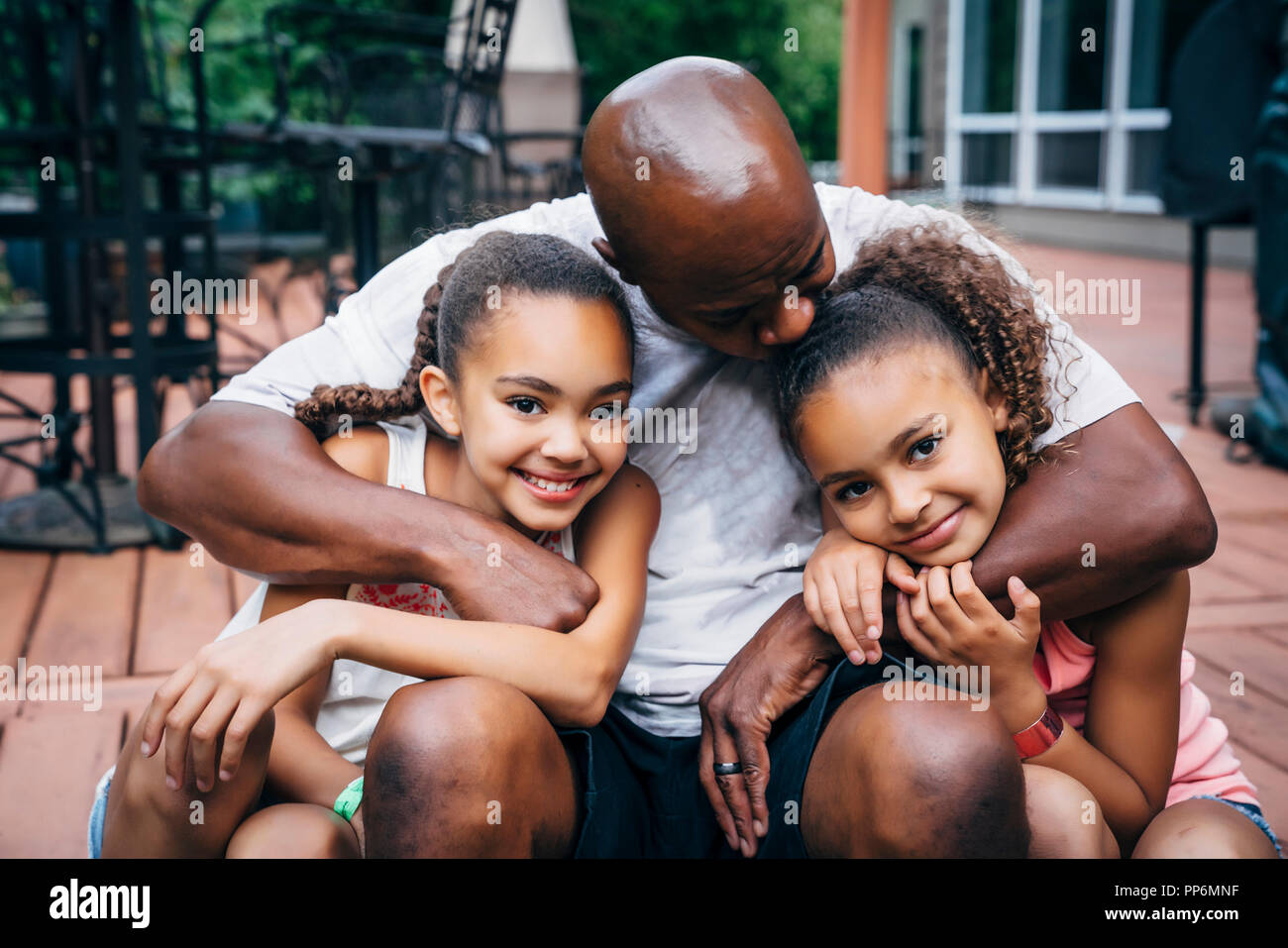 Portrait of happy dad hugging daughters in front of house Stock Photo ...