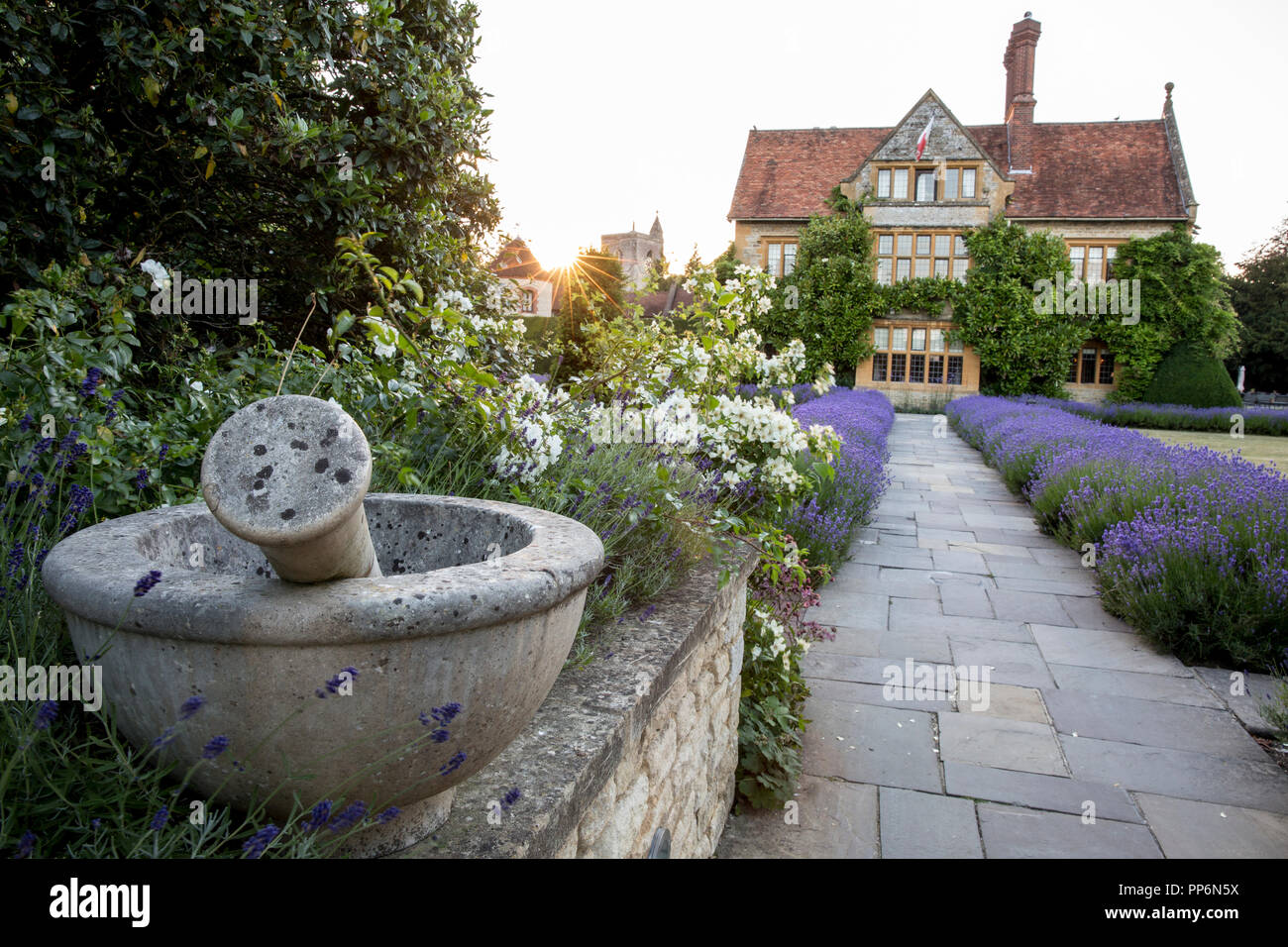 View of historic manor house from across a walled garden with lawn ...