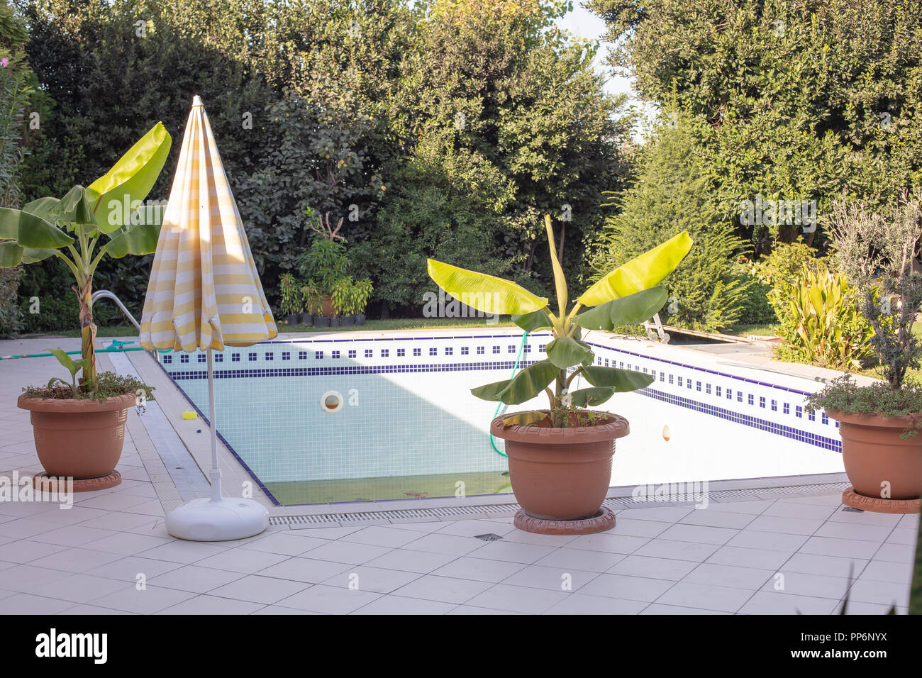 Swimming pool that is almost empty with dirty water end of the summer ...