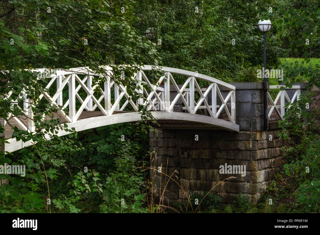 A fragment of the arch bridge across the ravine with a white railing on ...