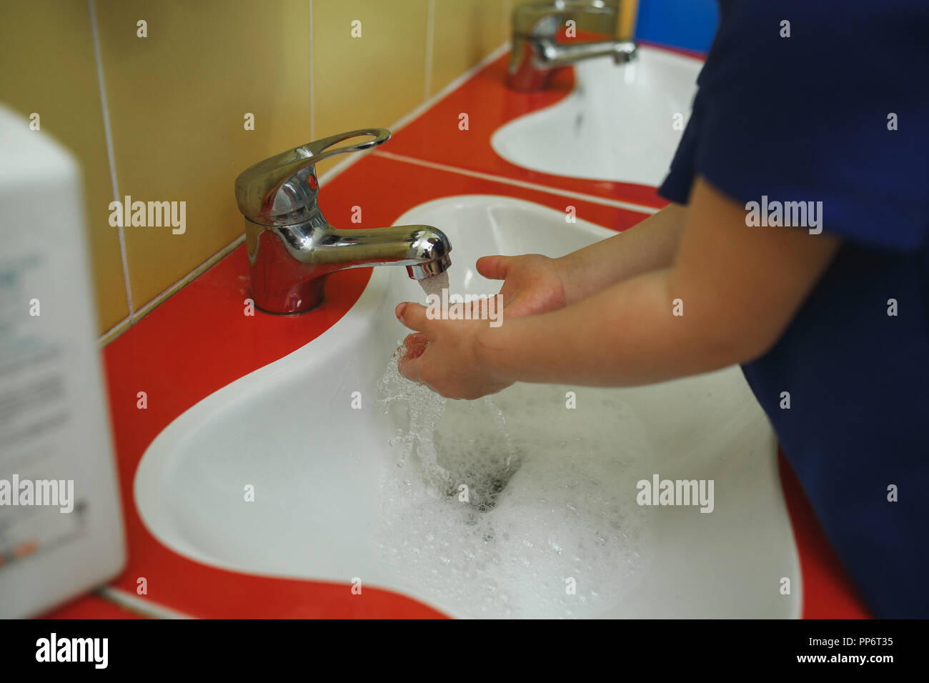 Child washing hands with soap in bathroom in kindergarten Stock Photo ...