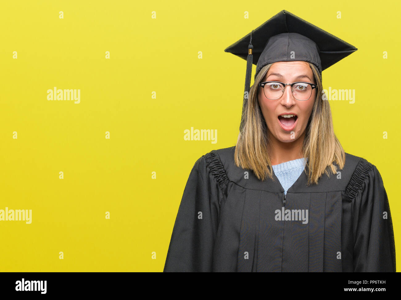 Young beautiful woman wearing graduated uniform over isolated ...