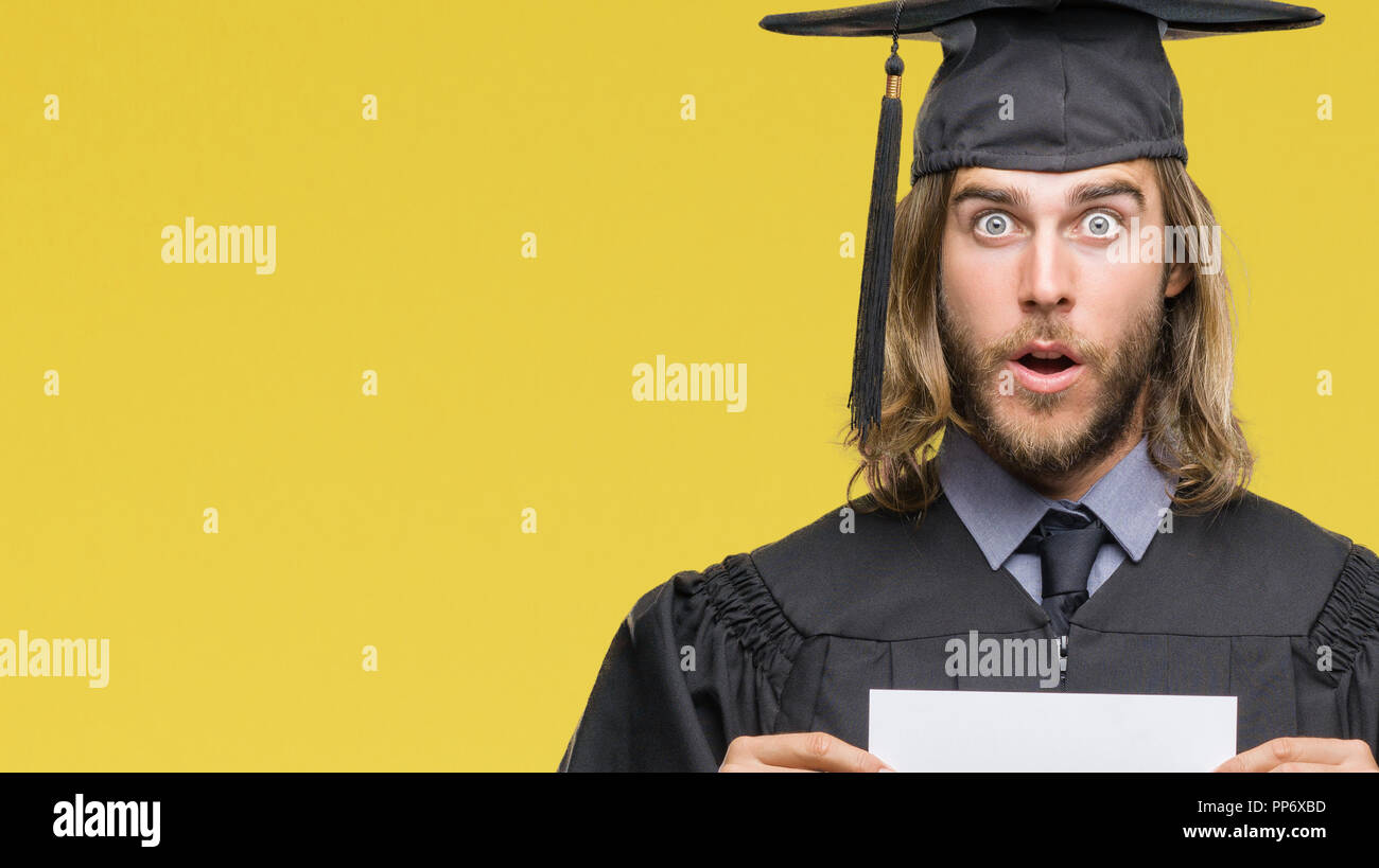 Young handsome graduate man with long hair holding blank paper over ...