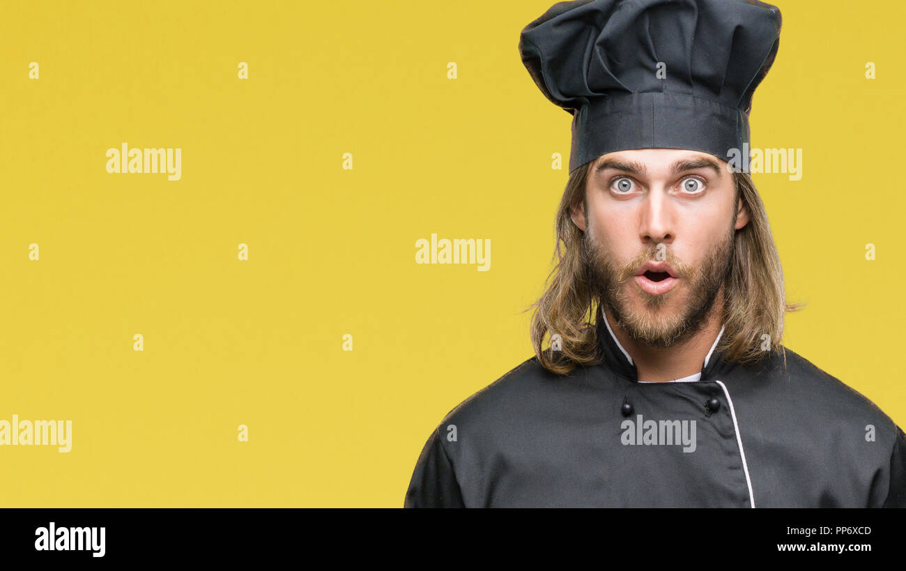 Young handsome cook man with long hair over isolated background afraid ...