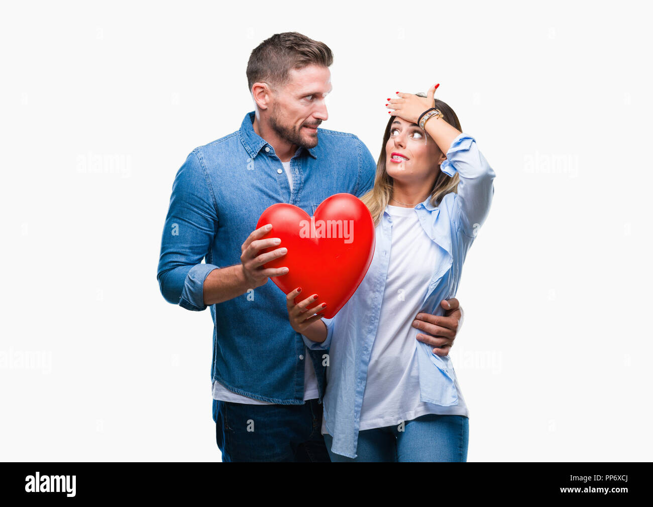 Young couple in love holding red heart over isolated background ...
