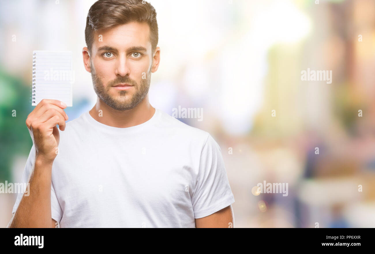Young handsome man holding notebook over isolated background with a ...