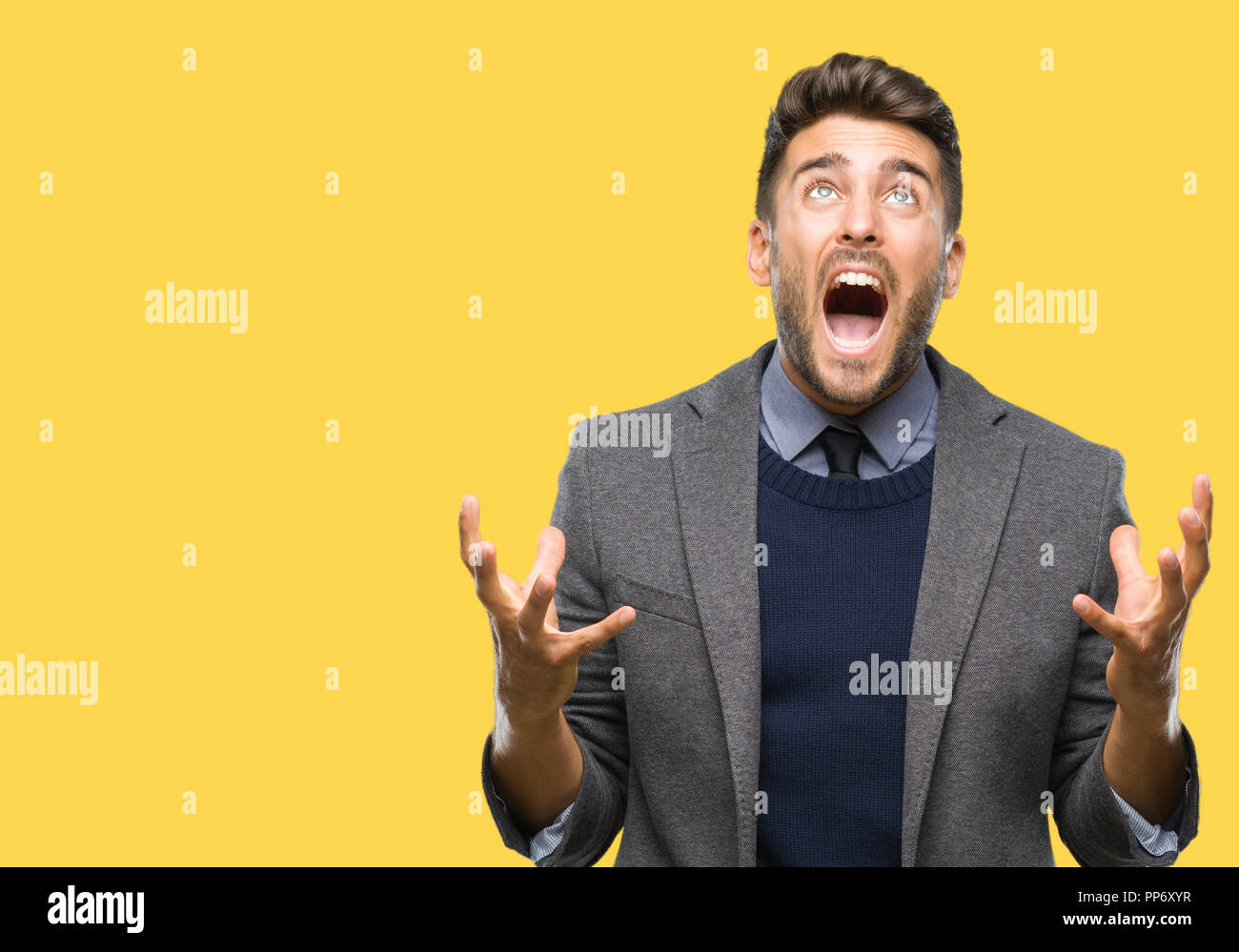 Young handsome business man over isolated background crazy and mad ...