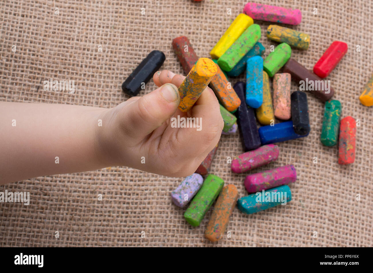 Used color crayons and a toddlers hand holding one Stock Photo - Alamy