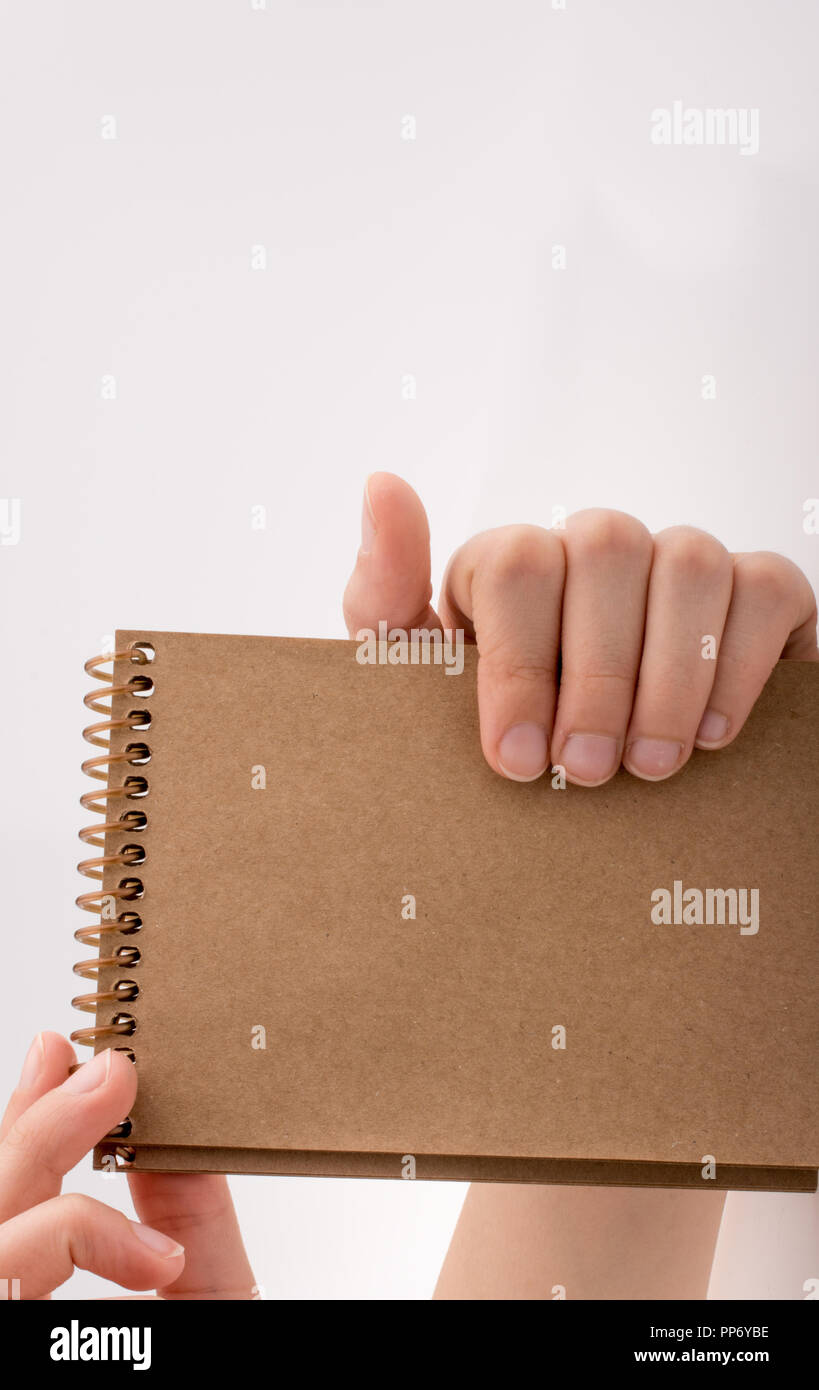 Hand holding brown color notebook on a white background Stock Photo - Alamy